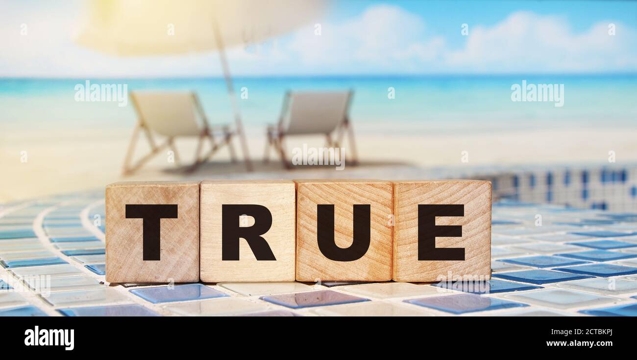 conceptual word true on wooden cubes on a beautiful ocean beach ...