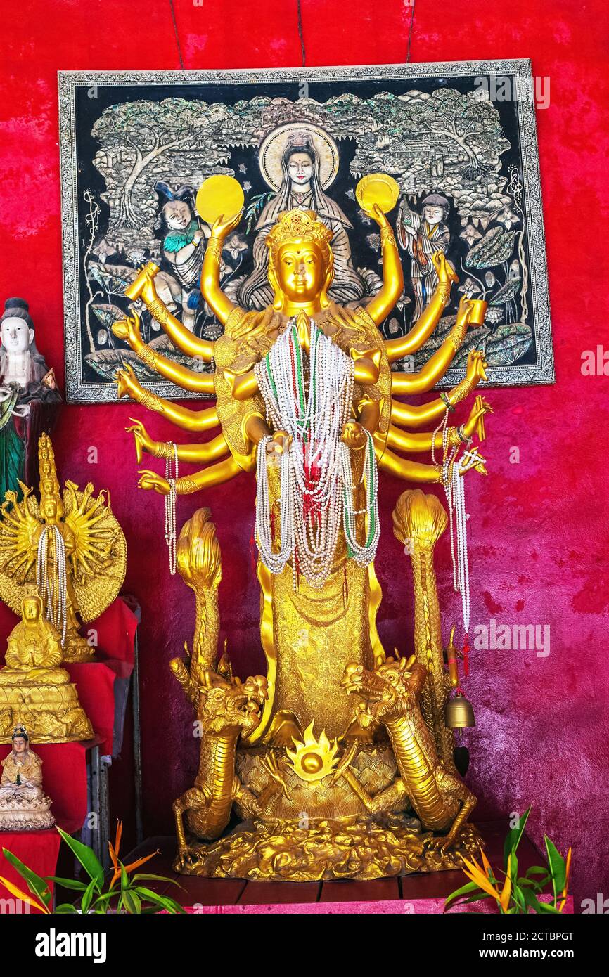 Old golden statue Guan Yin many-armed in Buddhist temple. Guanyin is ...