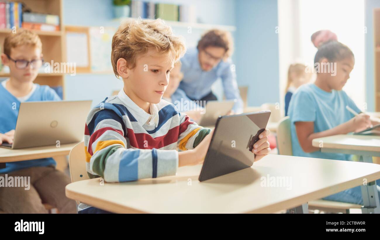 Elementary School Computer Science Class: Smart Boy Uses Digital Tablet ...