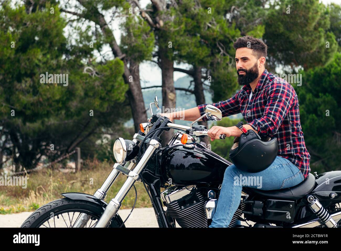 handsome bearded man riding his motorcycle with helmet hanging from his ...