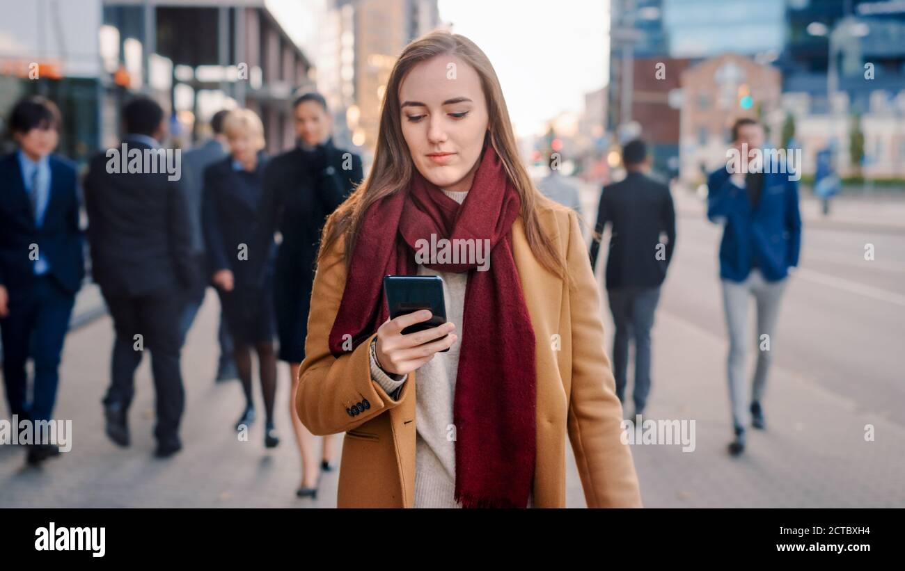 Young Smart Casually Dressed Female is Using a Smartphone on a Street ...