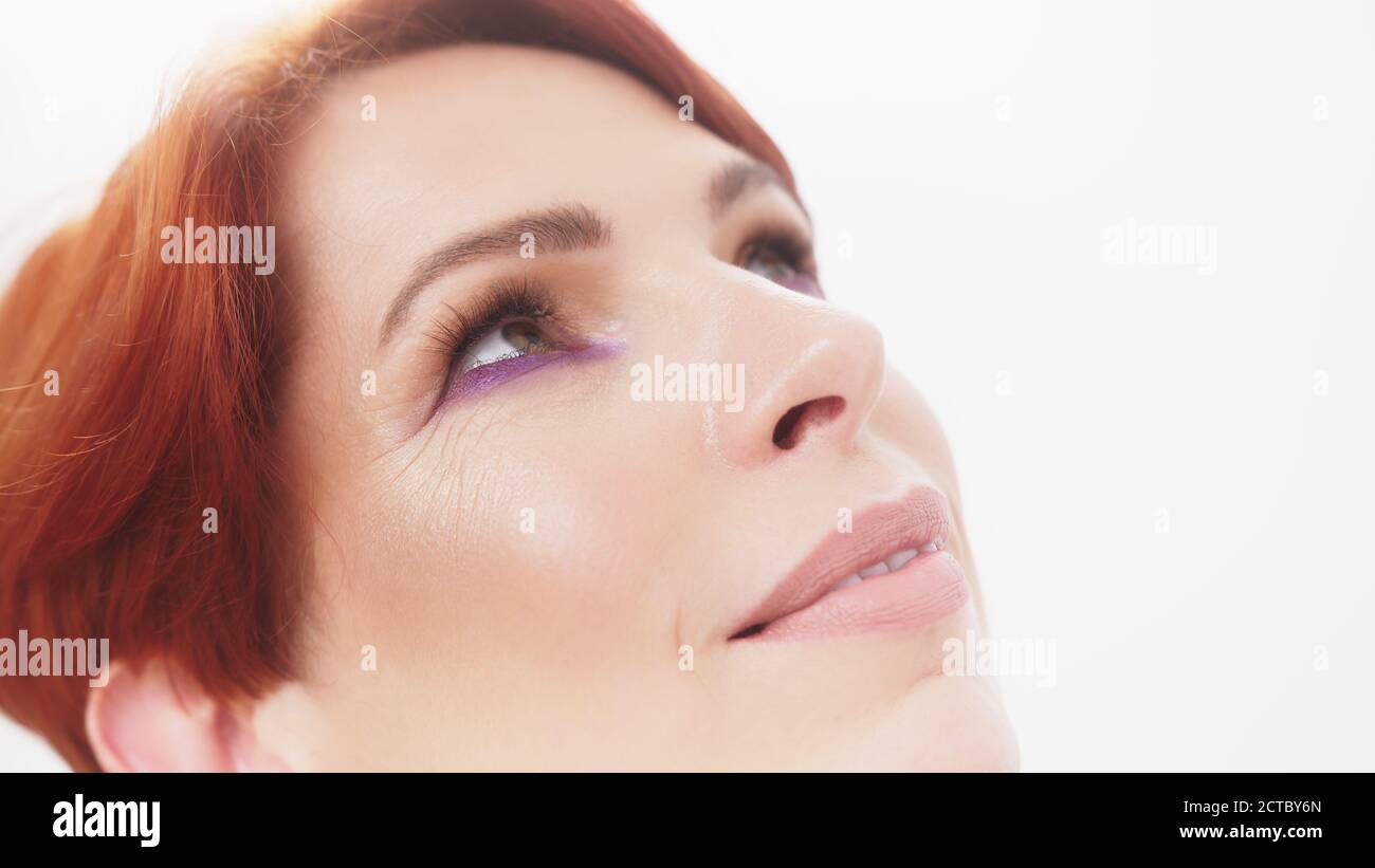 Close up, redhead woman with wrinkles around the eyes and clear skin ...