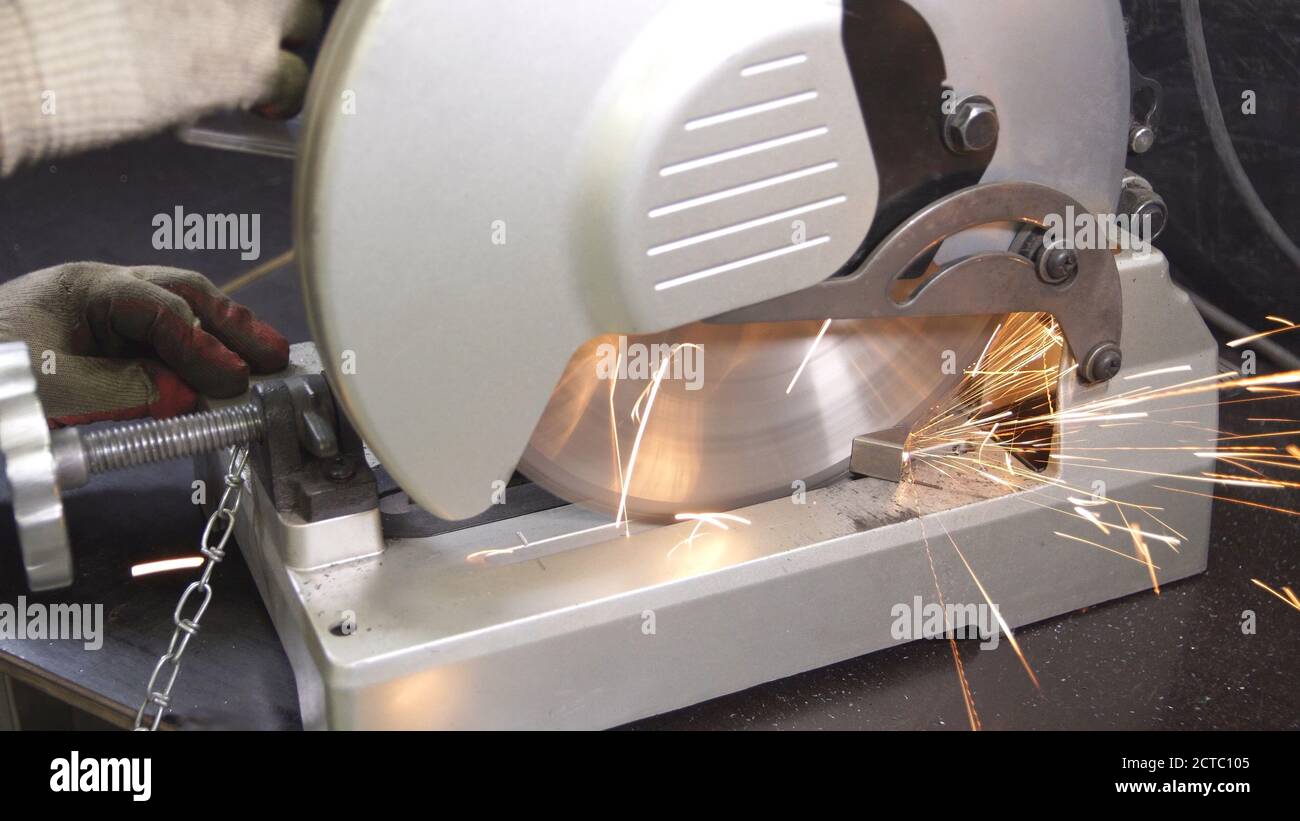 Grinding in steel manufactory. Working man with big saw cutting metal ...