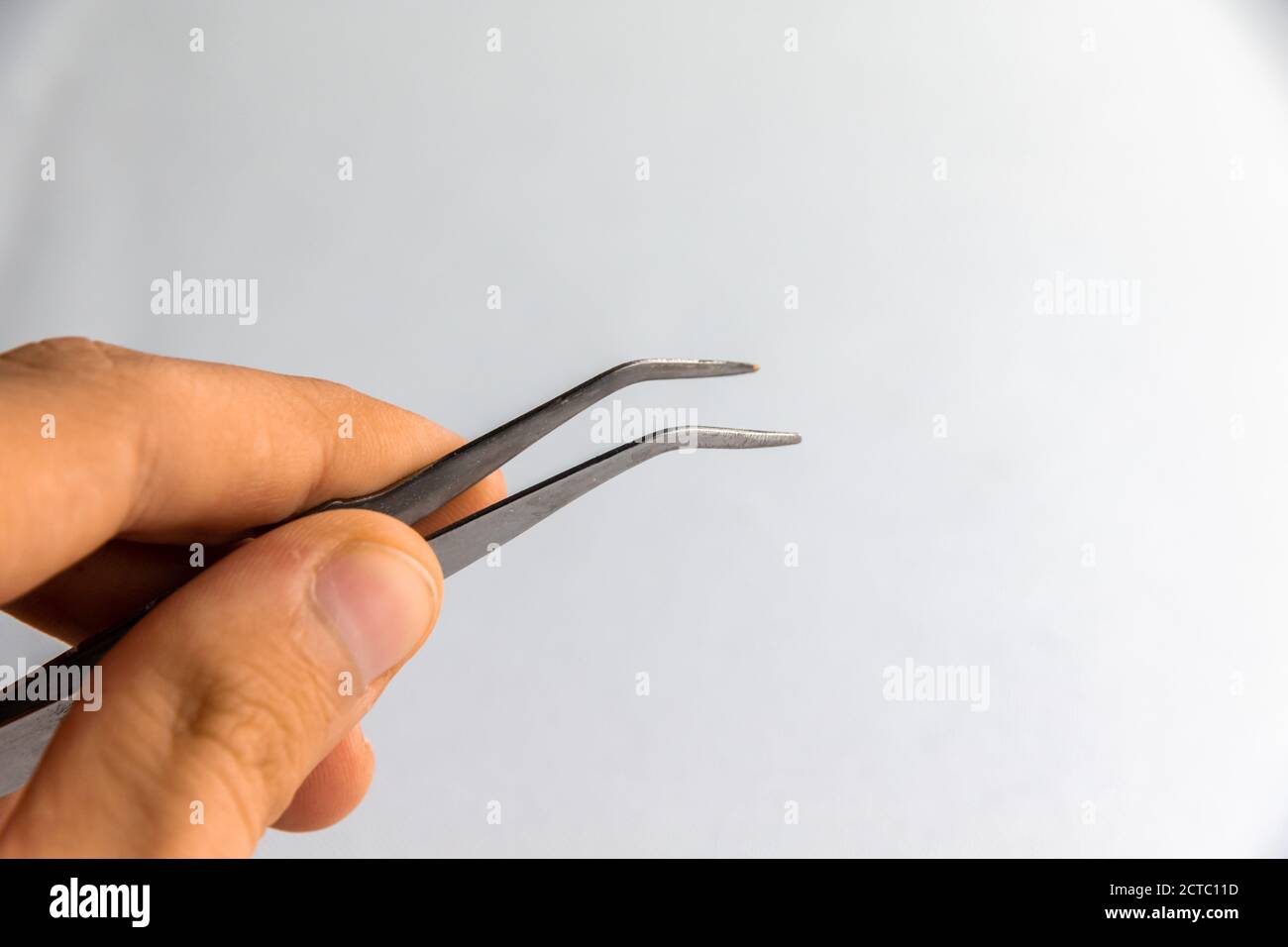 A gloved hand holding tweezers against white background Stock Photo - Alamy