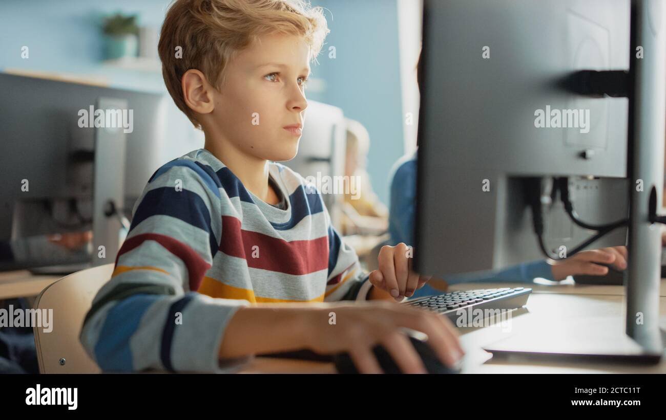 Elementary School Classroom: Smart Boy Uses Personal Computer, Learning ...