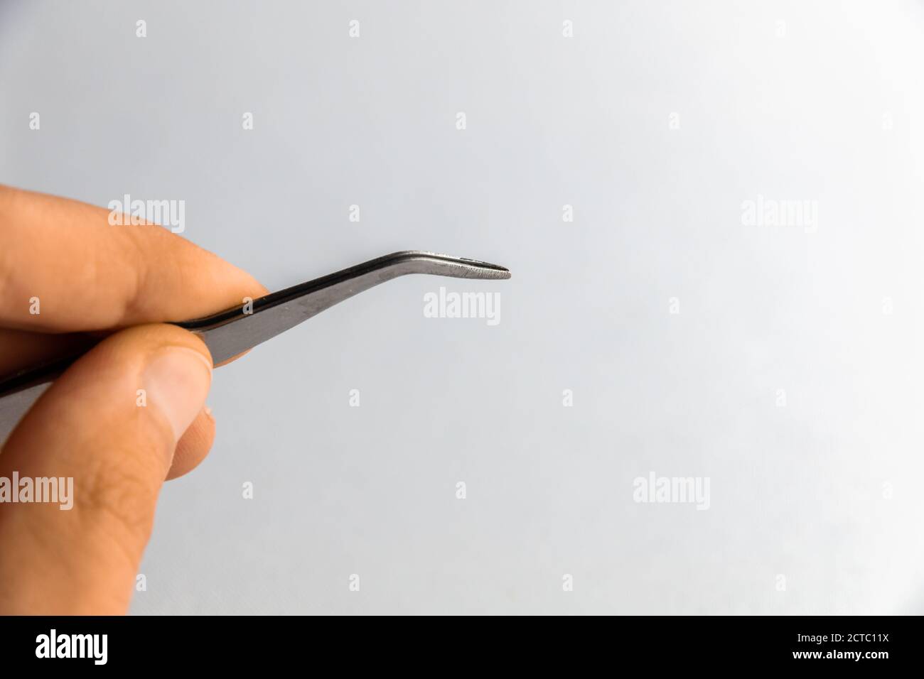 A gloved hand holding tweezers against white background Stock Photo - Alamy