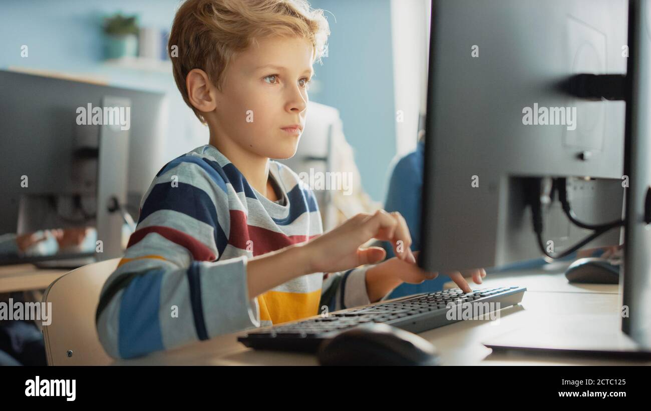 Elementary School Classroom: Smart Boy Uses Personal Computer, Learning ...