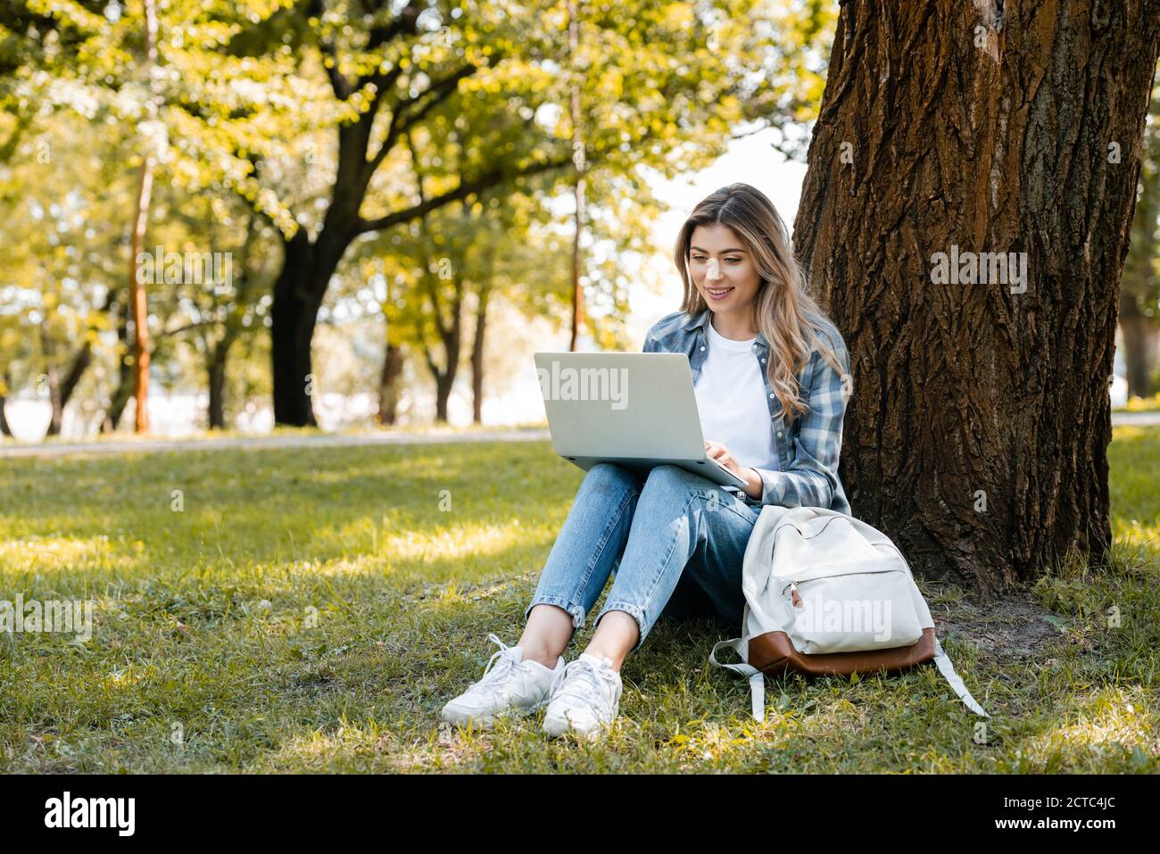 Woman on laptop under tree hi-res stock photography and images - Alamy