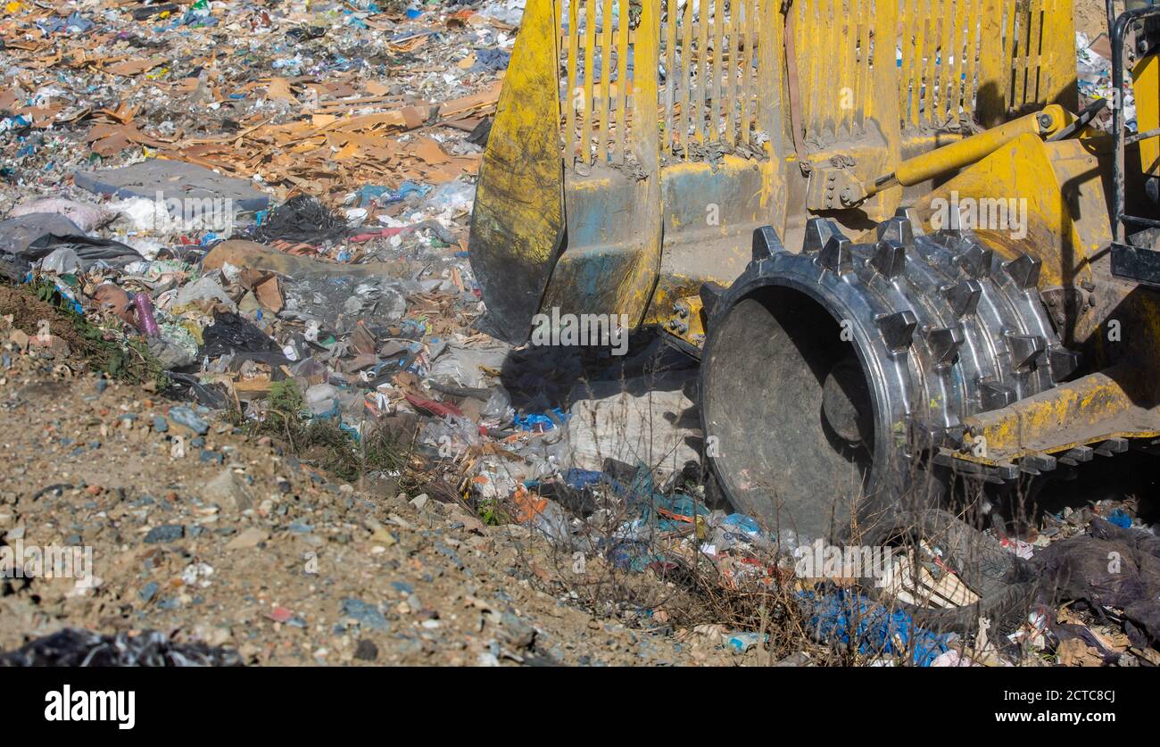 Huge bulldozer at a landfill or dump cleaning household garbage ...