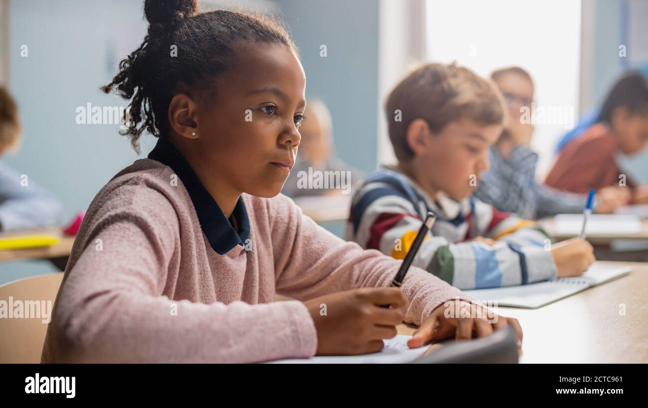 In Elementary School Classroom Brilliant Black Girl Writes in Exercise ...