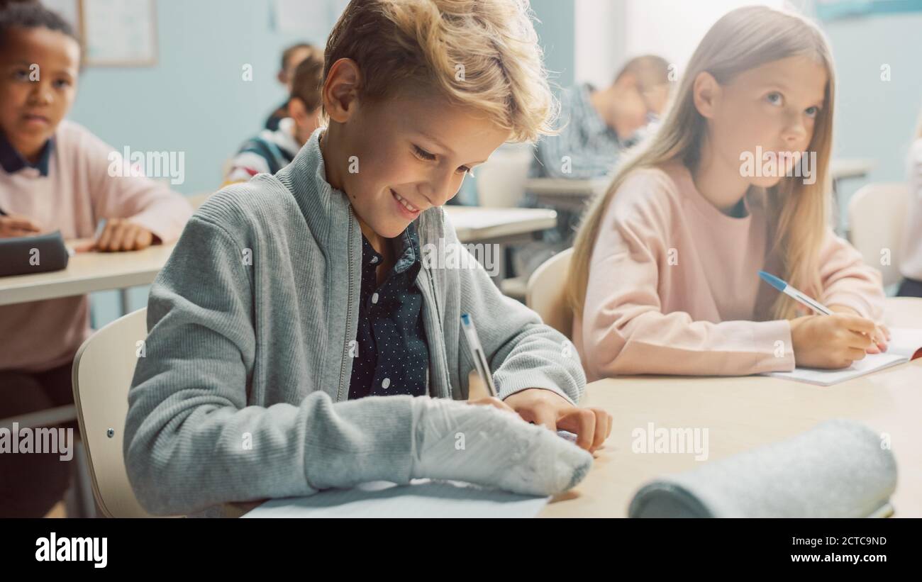 In Elementary School Classroom Brilliant Caucasian Boy Writes in ...