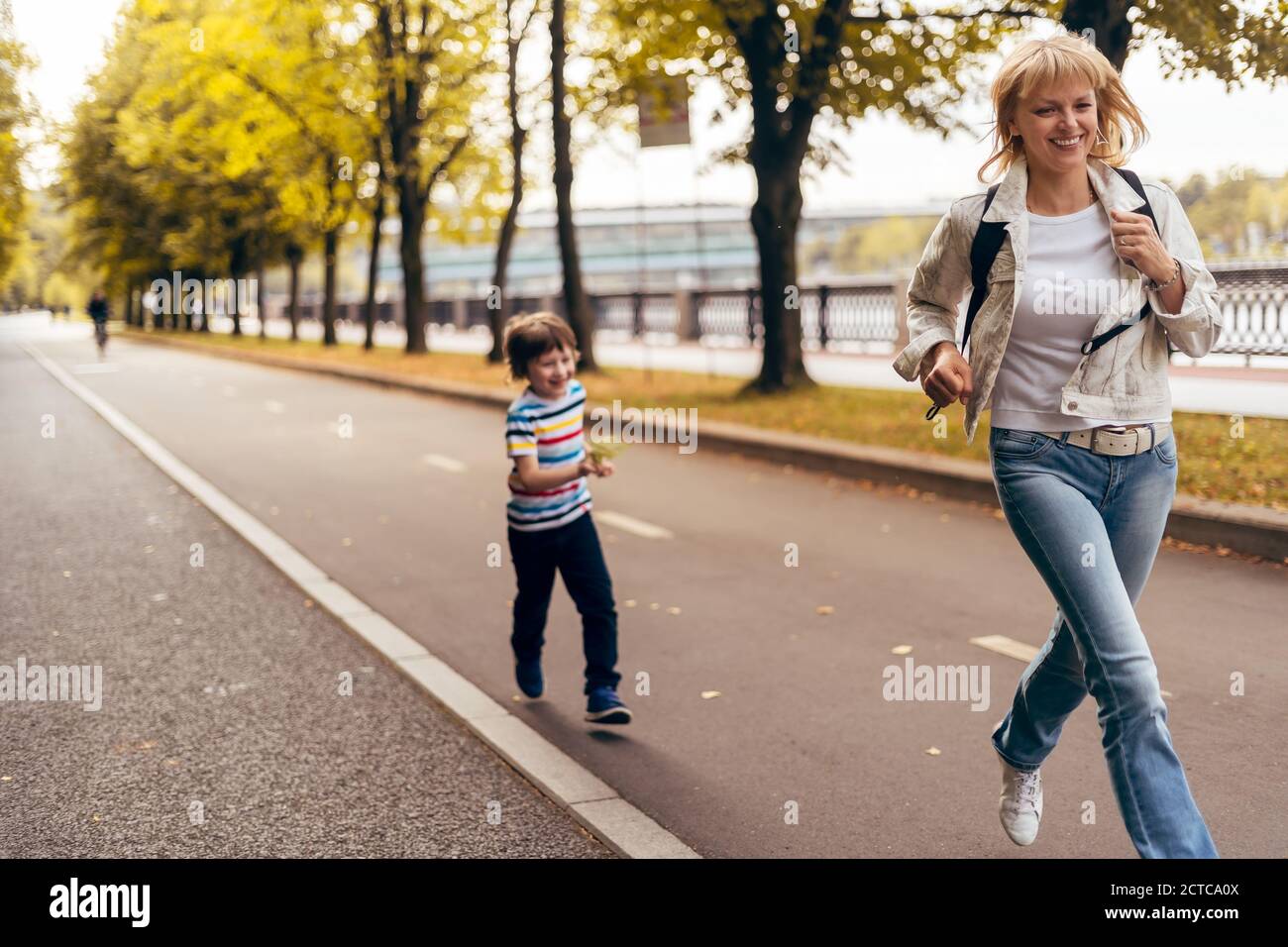 Smiling little kid boy and his grandmother having fun in autumn park ...