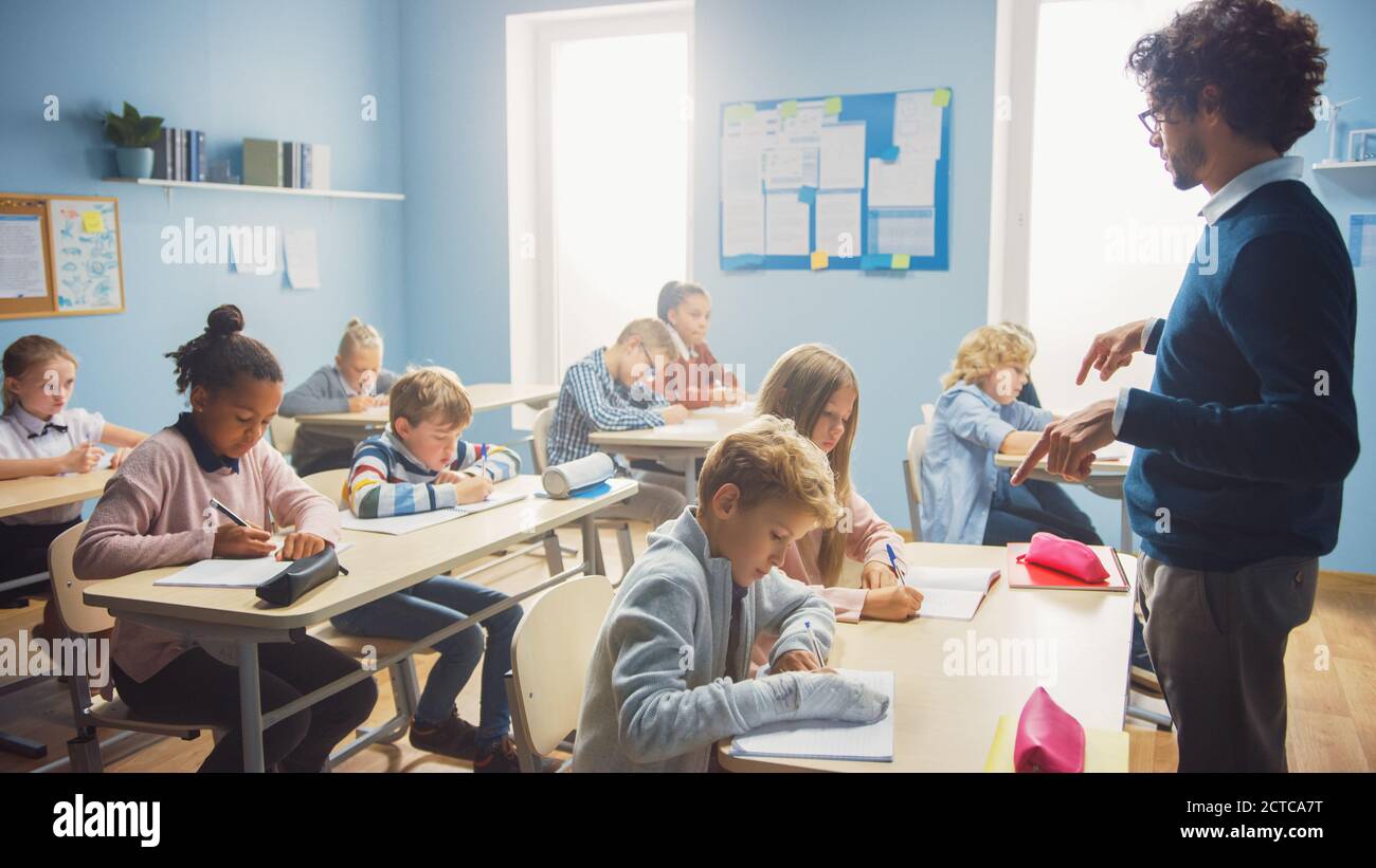 In Elementary School Class: Enthusiastic Teacher walks between Rows of ...