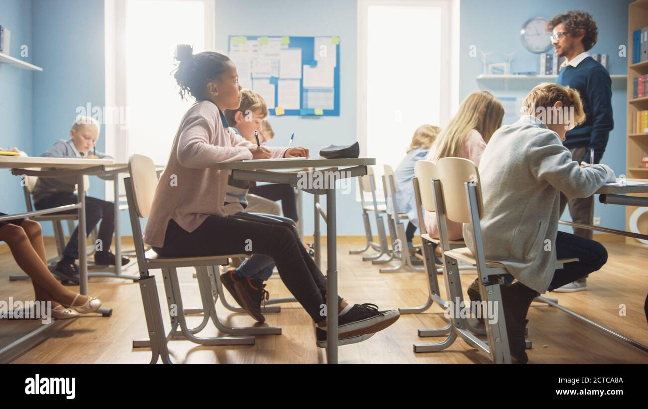 In Elementary School Class: Enthusiastic Teacher walks between Rows of ...