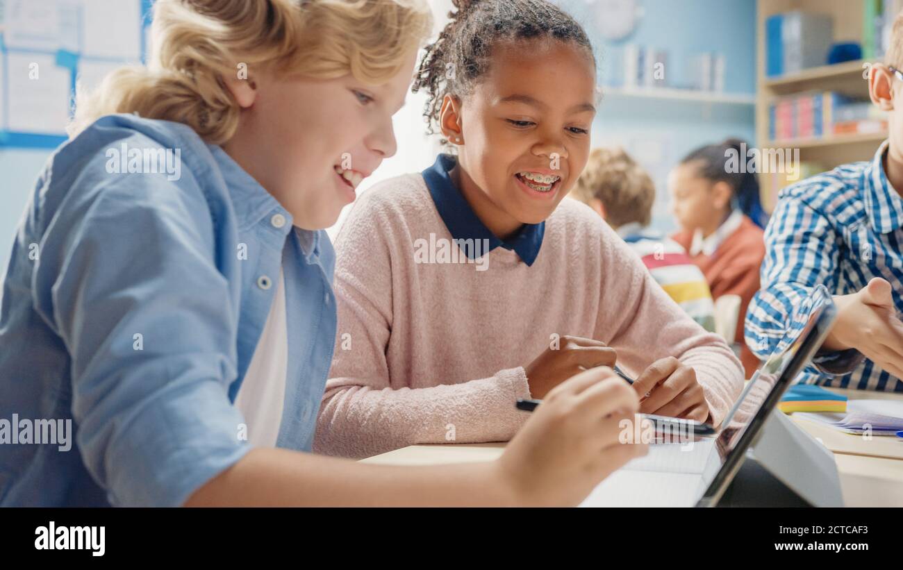 In the Elementary School: Girl and a Boy Work as a Team Using Tablet ...