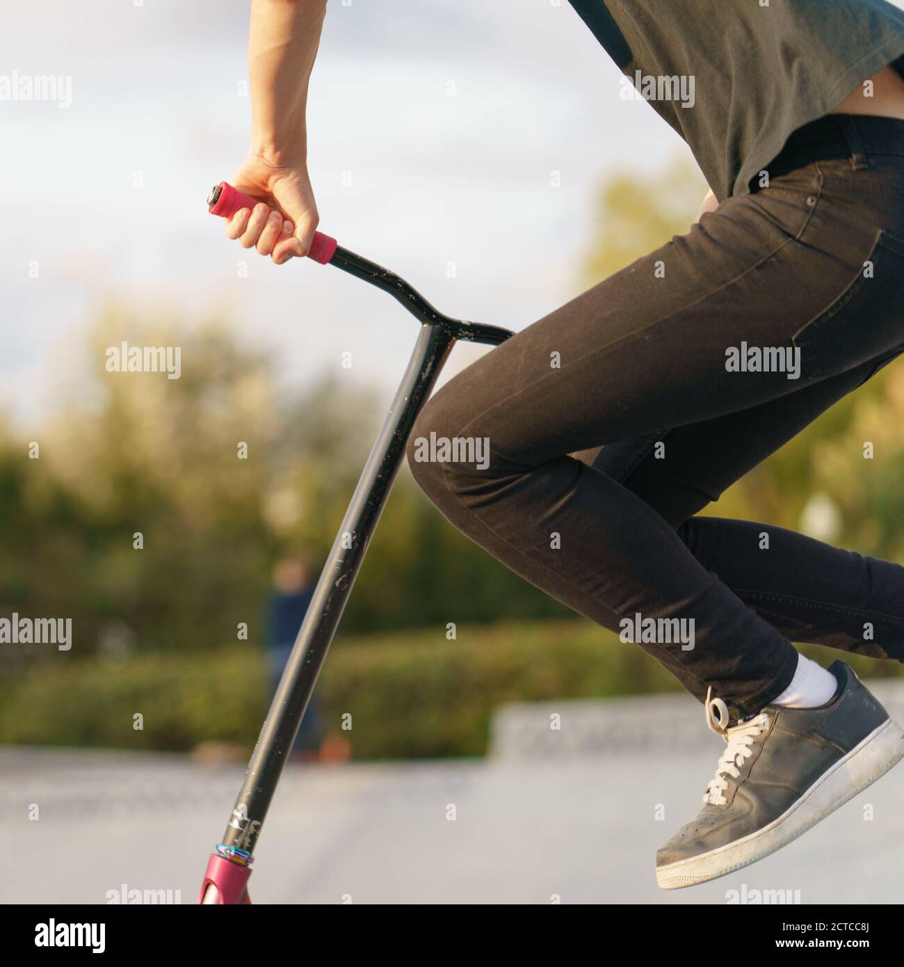 Teenager performs a trick in the city skate park. Push scooter. He ...