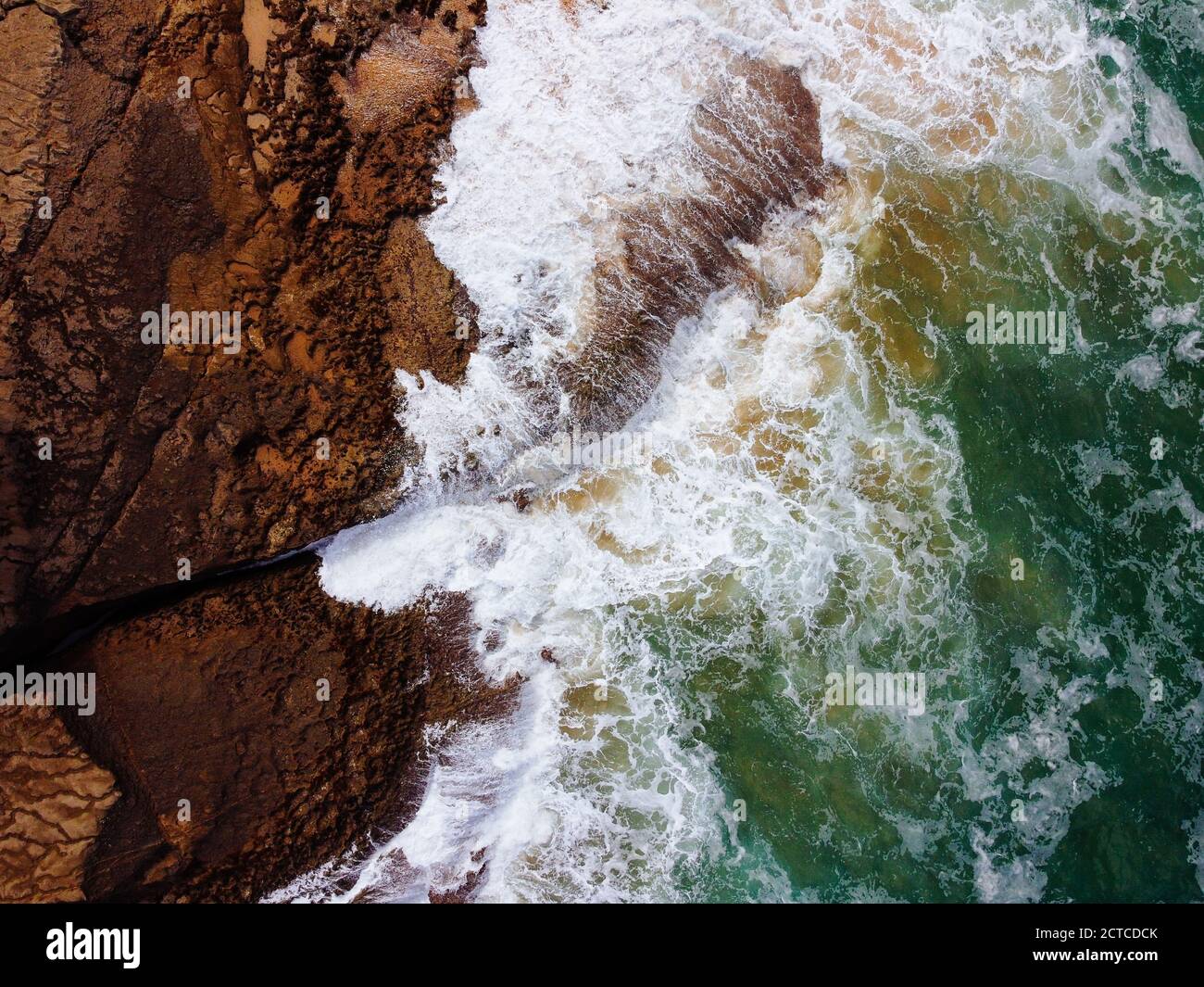 Aerial top view of sea waves hitting rocks on the cliffs. Overhead ...
