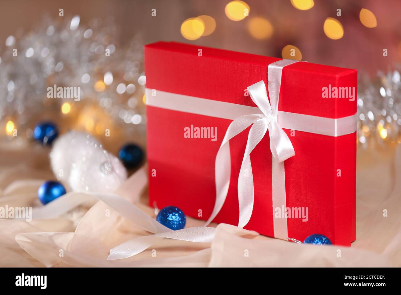 Red Christmas gift box with white ribbon on a table Stock Photo - Alamy
