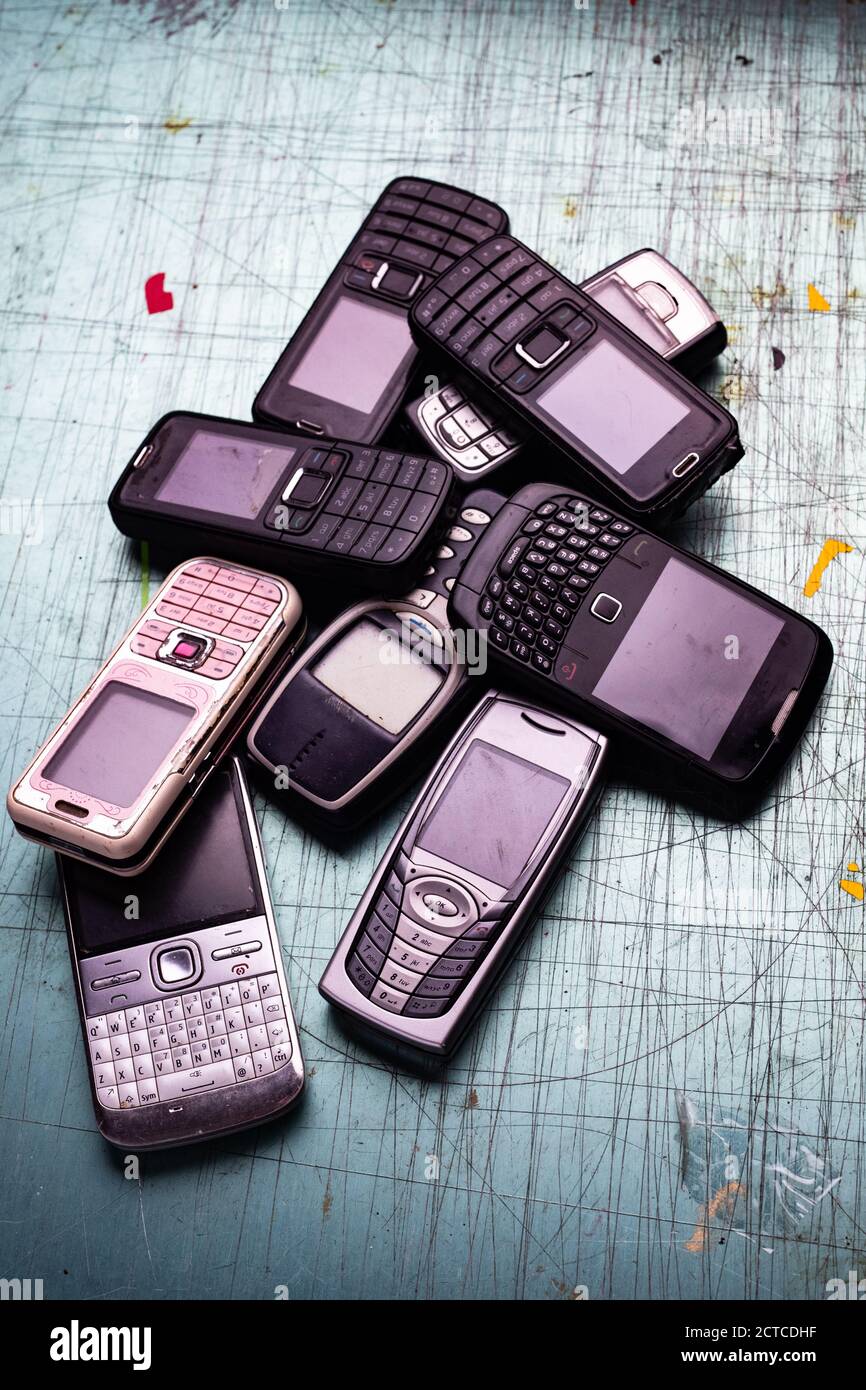 old, obsolete and broken cellphones scratched metal background Stock ...