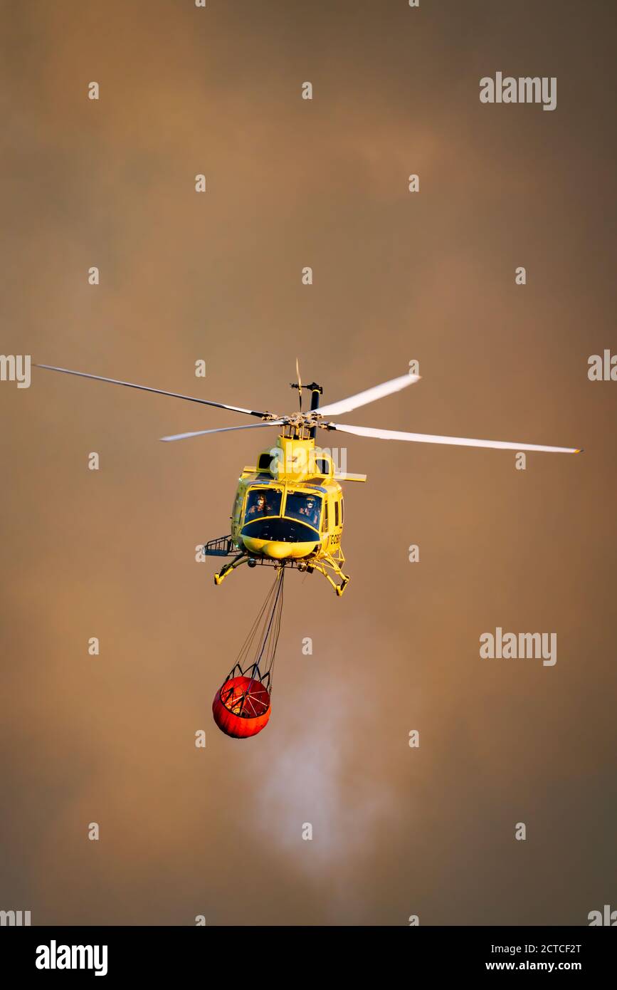Fire fighter helicopter against dark smoke with water tank Stock Photo ...