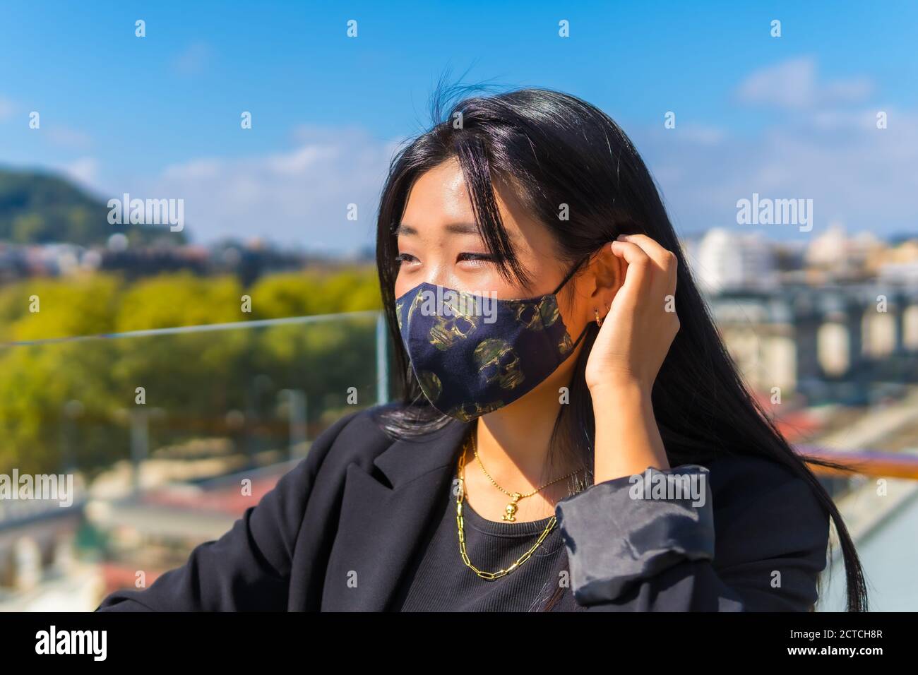 Closeup of a beautiful Chinese wearing a patterned face mask outdoors ...
