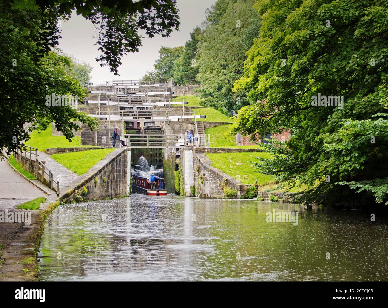 A canal longboat entering five-rise locks in light rain Stock Photo - Alamy