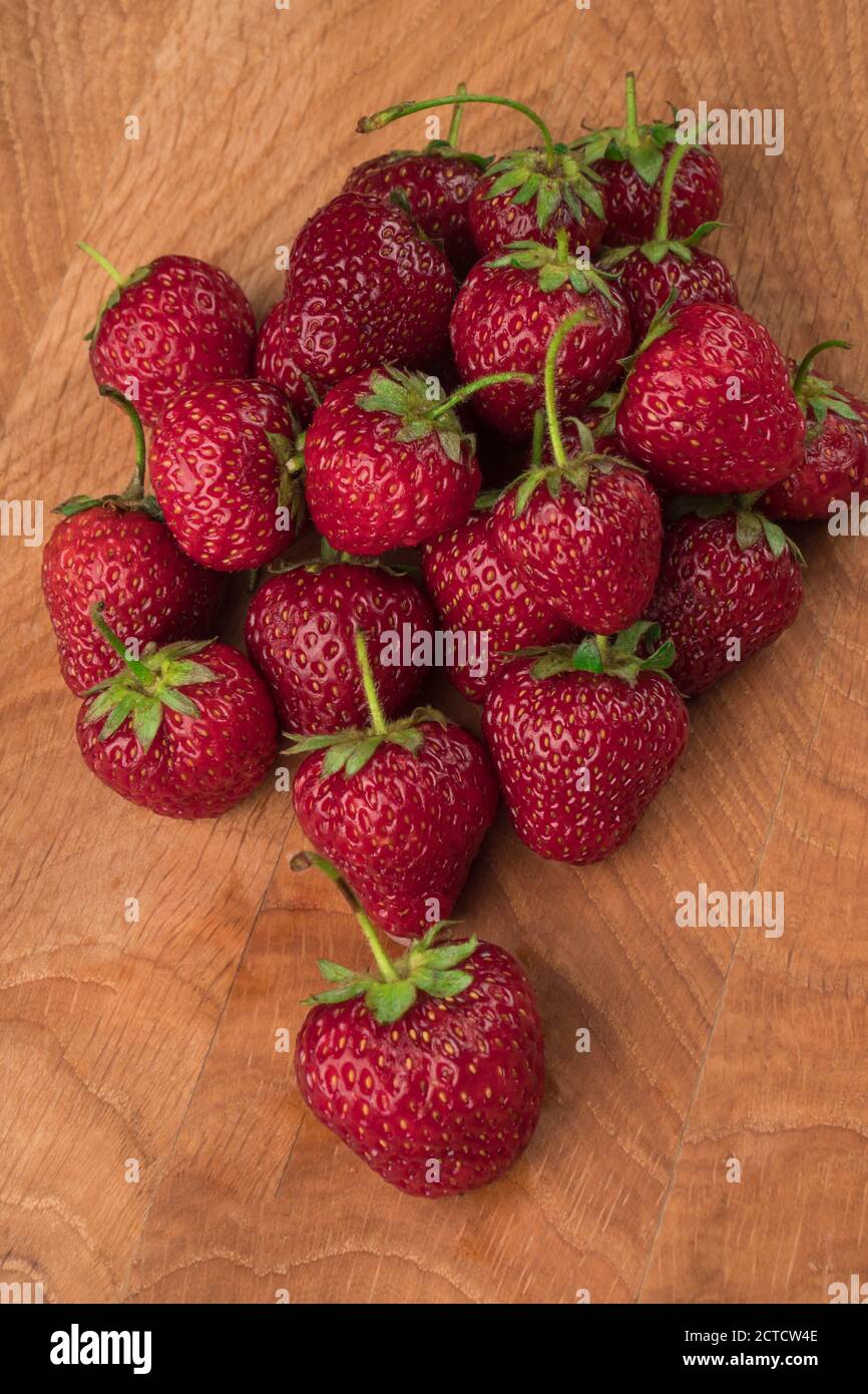A bunch of delicious juicy red strawberries, lies on a wooden board ...