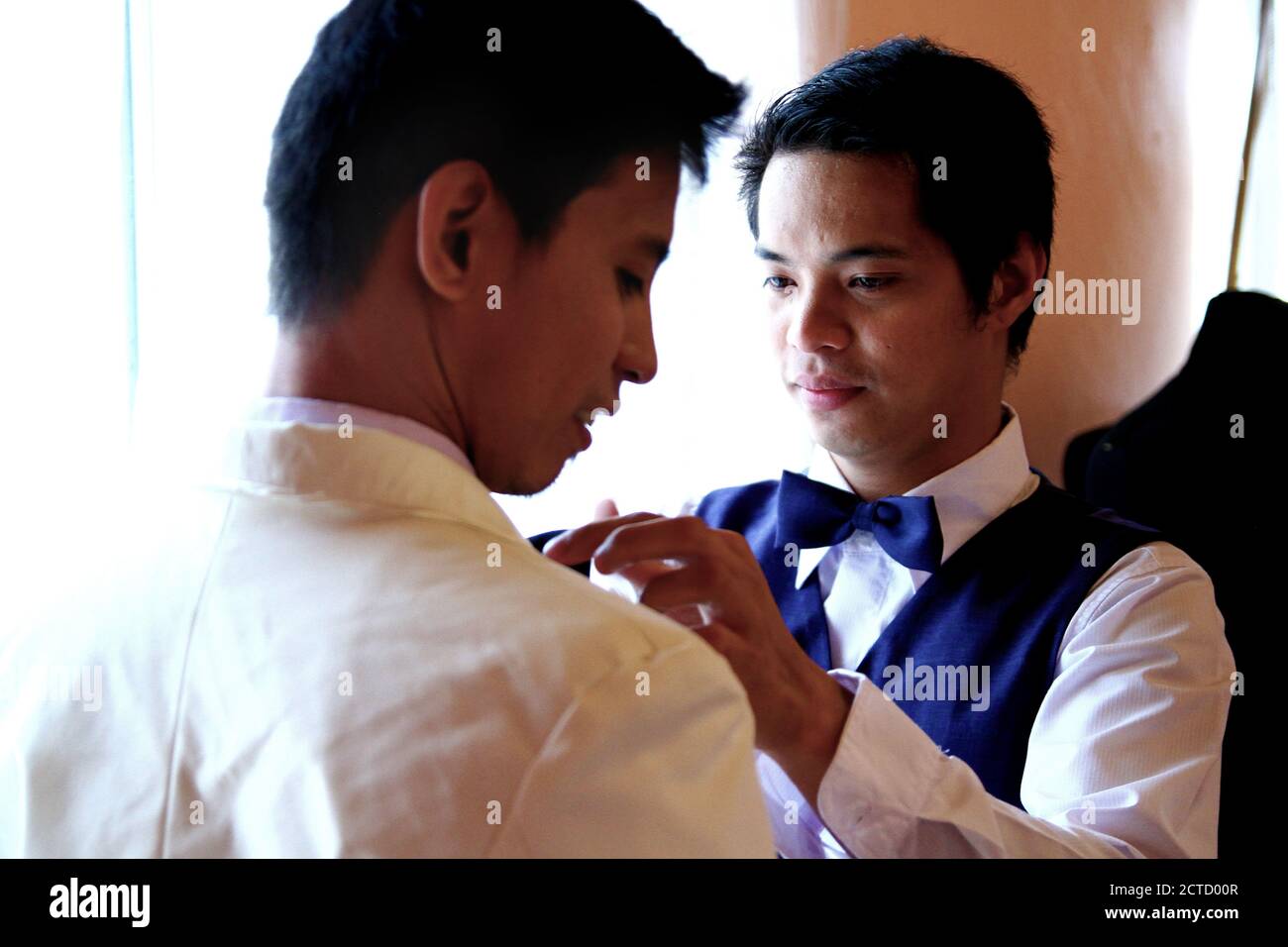 stylish groomsmen helping happy groom getting ready in the morning for ...