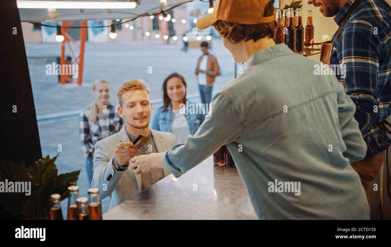 Food Truck Employee Hands Out a Freshly Made Burger to Happy Young Man ...