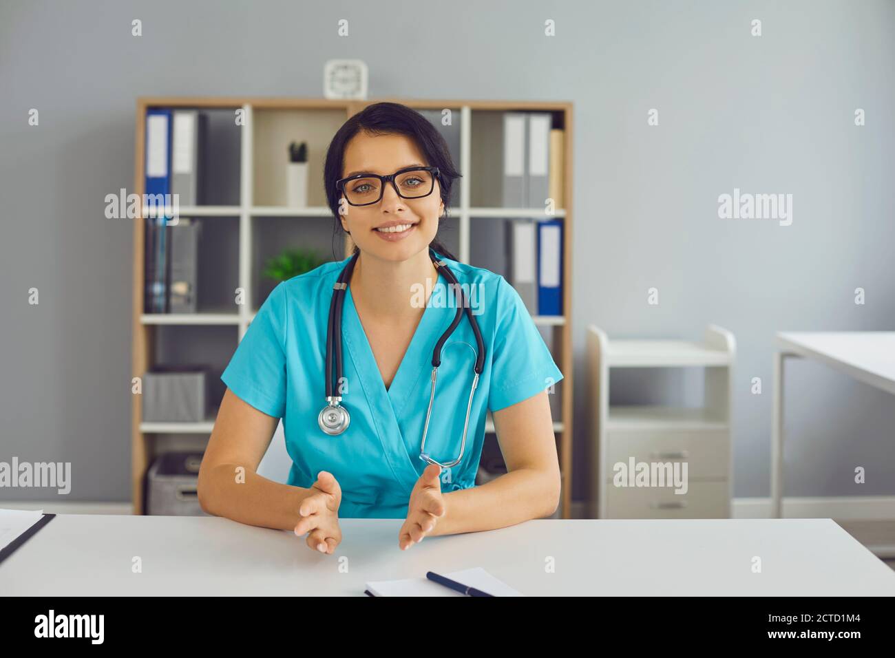 Young doctor sitting at desk and giving consultation to patient during ...