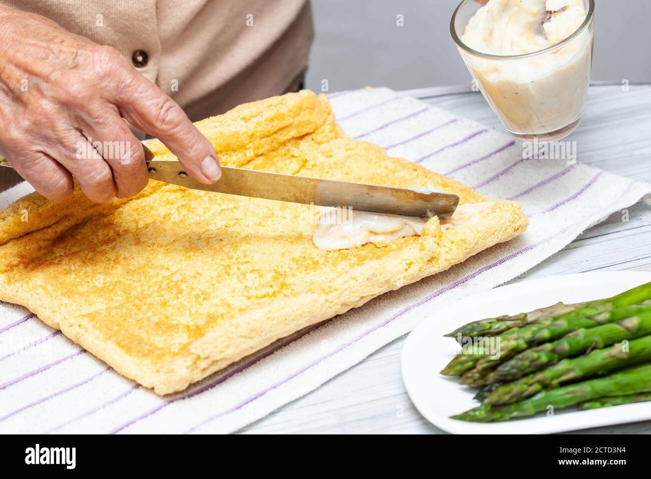 Close up of a senior woman hands stuffing a just baked sponge cake ...