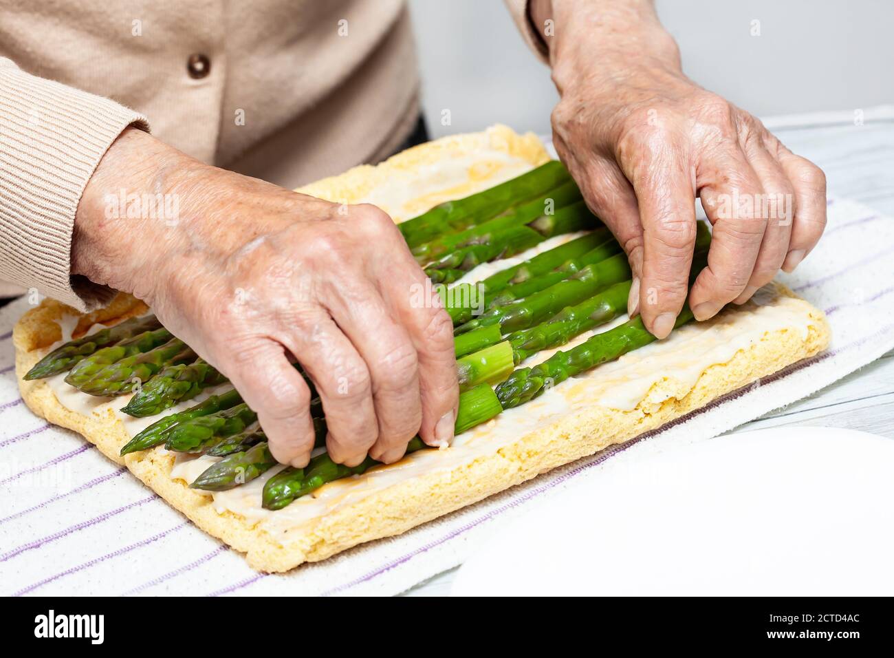 Close up of a senior woman hands stuffing a just baked sponge cake ...
