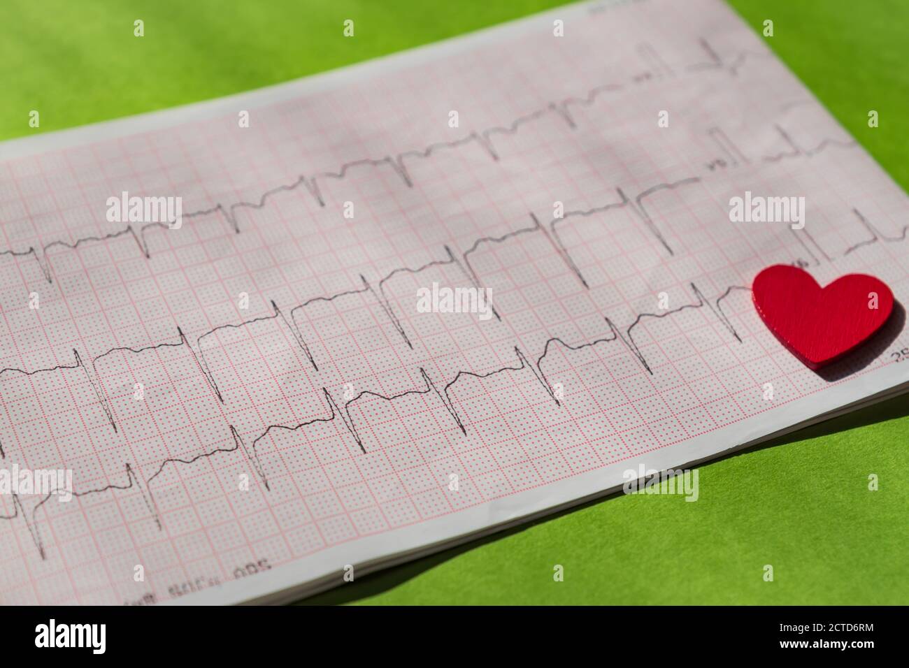 close up of an electrocardiogram in paper form vith red wooden heart ...