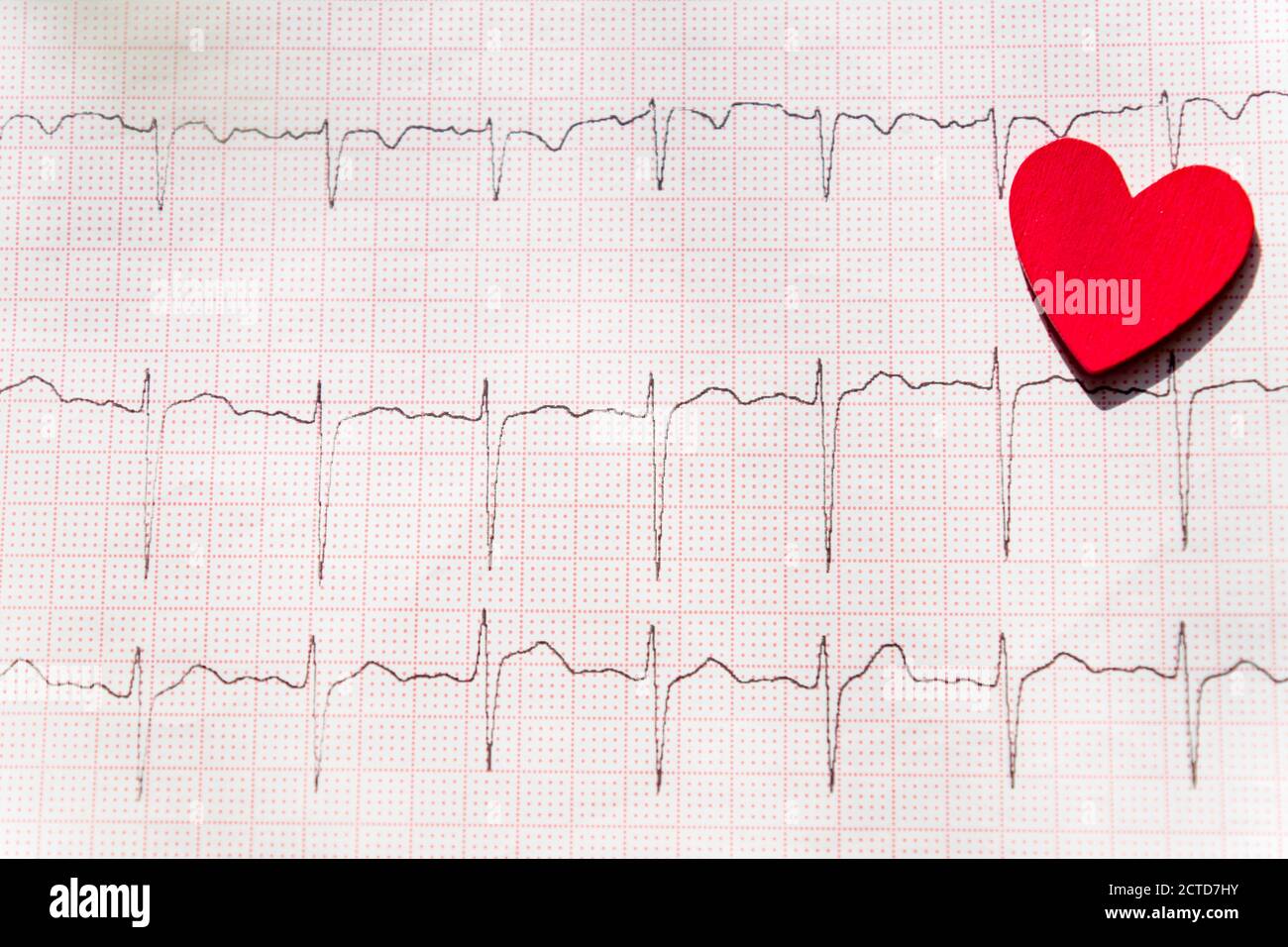 close up of an electrocardiogram in paper form vith red wooden heart ...