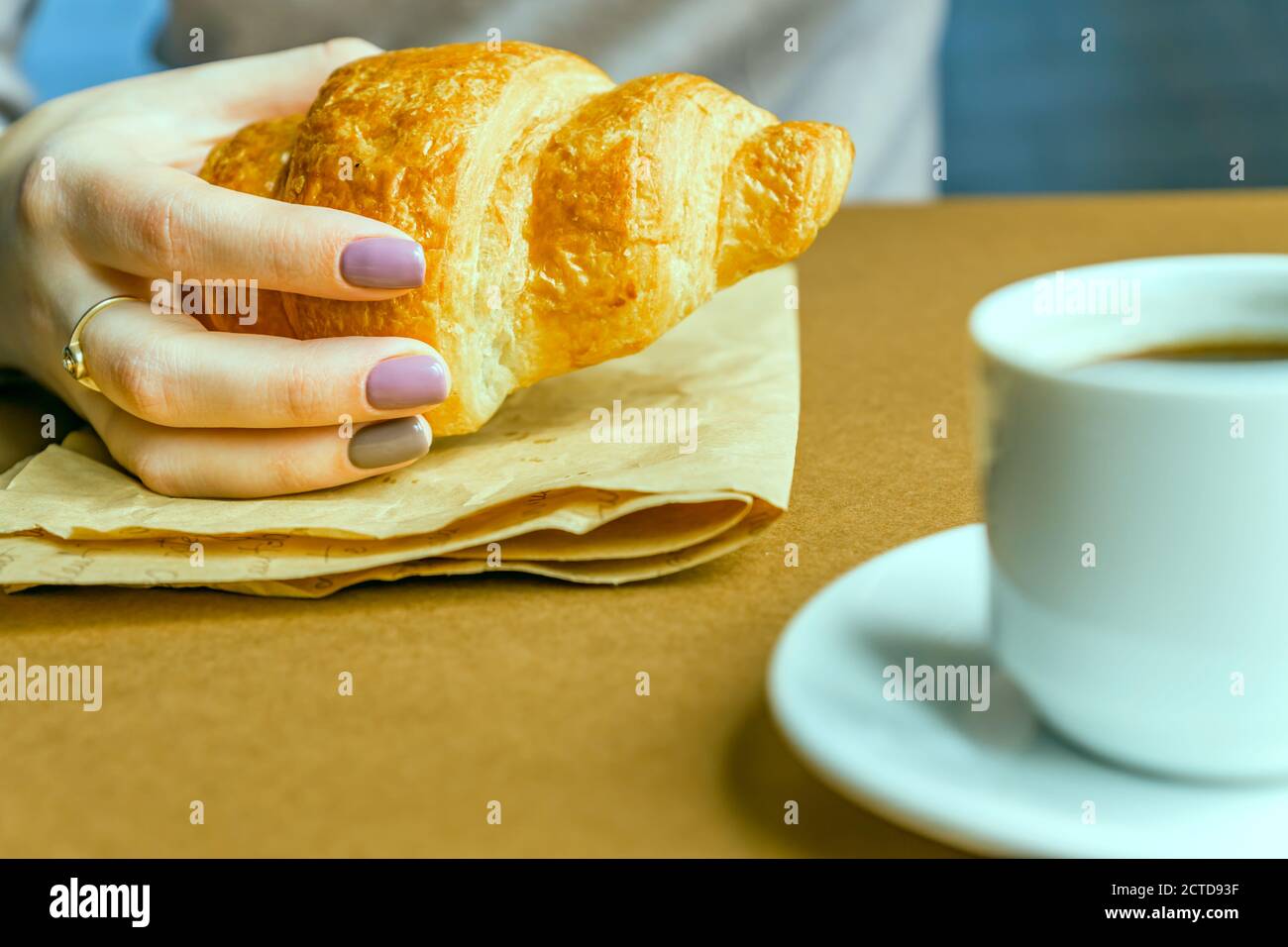 Female hands with manicure holding croissant. Breakfast in french style ...