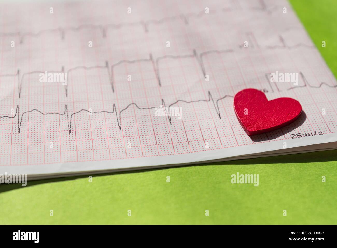 close up of an electrocardiogram in paper form vith red wooden heart ...