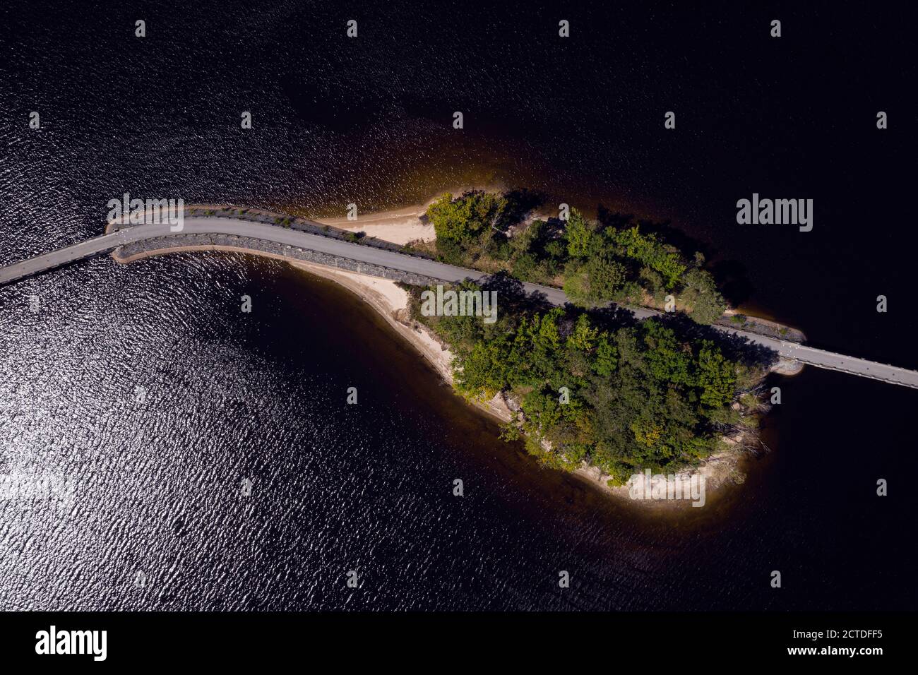 Aerial top view photo of a tiny green forest covered island crossed by ...