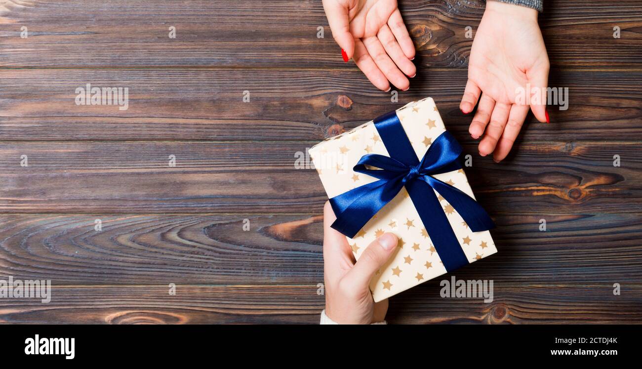 Top view of a woman and a man giving and receiving a present on wooden ...