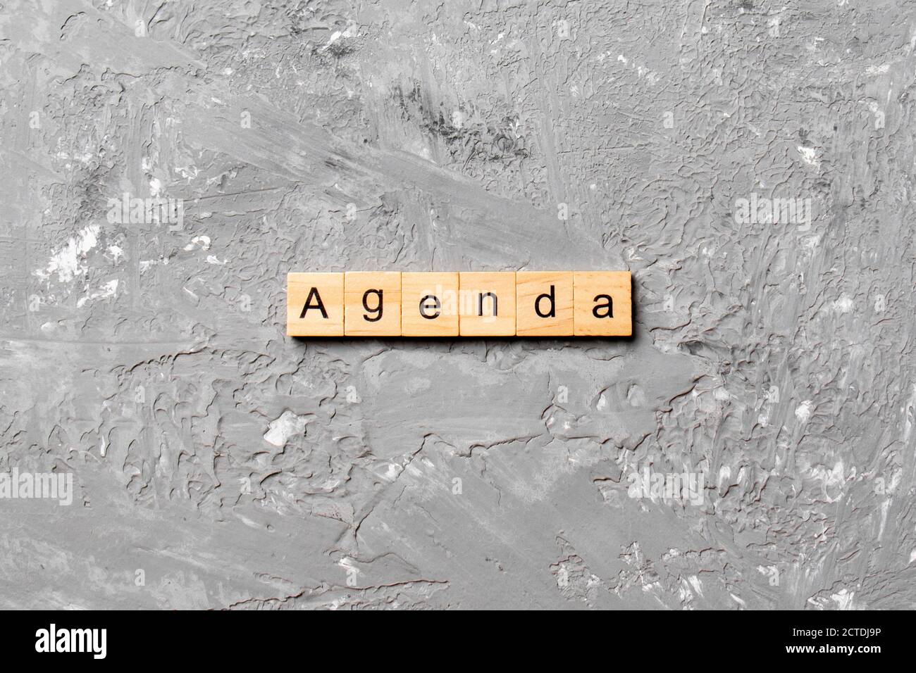 AGENDA word written on wood block. AGENDA text on cement table for your ...
