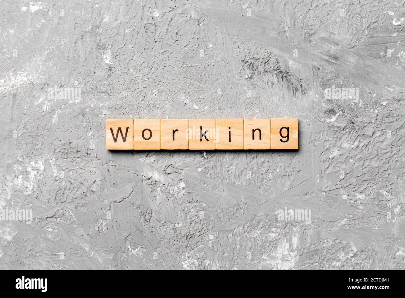 WORKING word written on wood block. WORKING text on cement table for ...