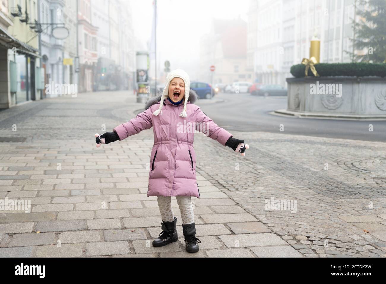 Cute liitle sad lost caucasian girl in warm long pink jacket and hat ...