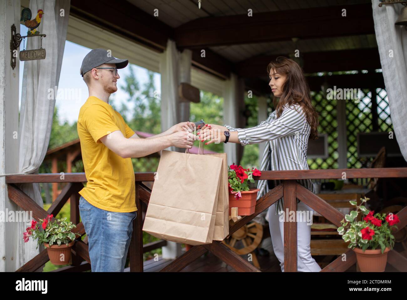 Cute woman customer receiving order from delivery man, pays for order ...