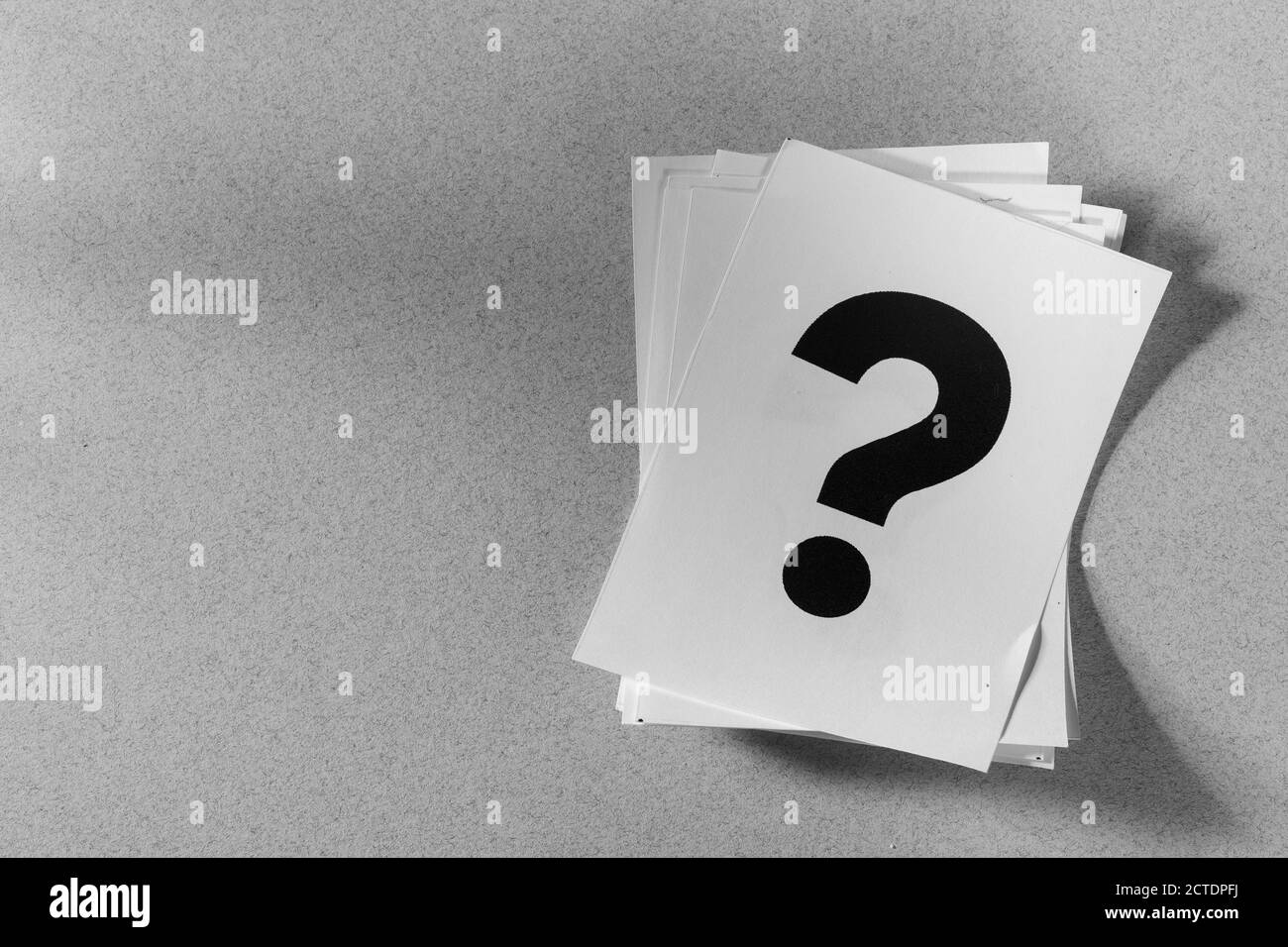 Grayscale shot of a pile of papers with a printed question mark - the ...