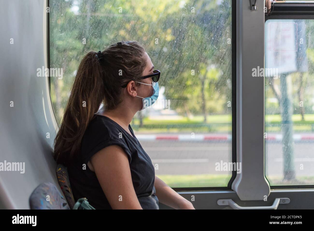 Female wearing a mask preventing contagion sitting in a bus, social ...