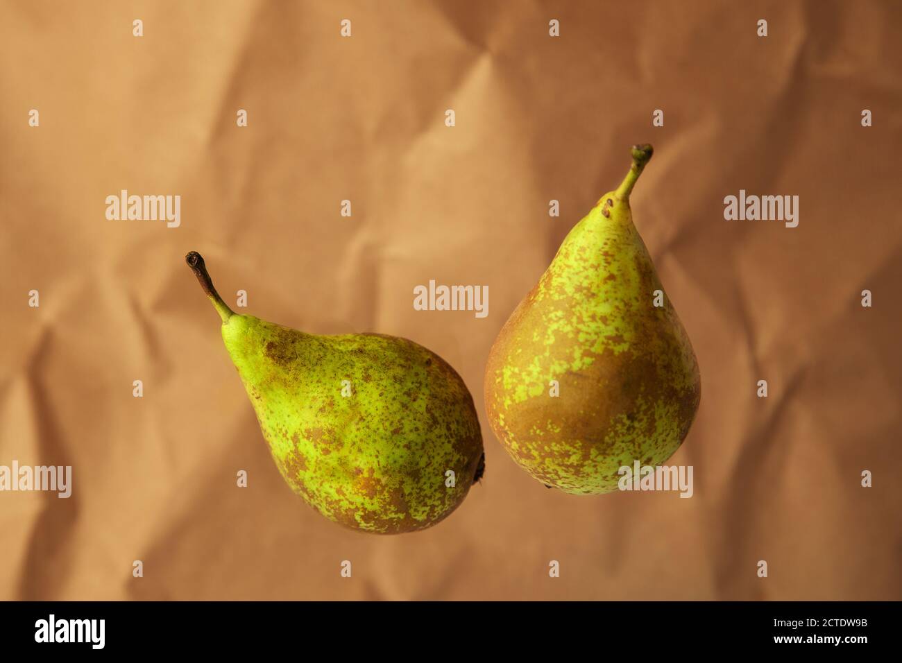 Closeup shot of two ripe pears with a crumpled paper background behind ...