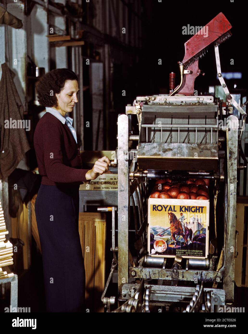 Operating a machine for putting tops on crates at a co-op orange ...