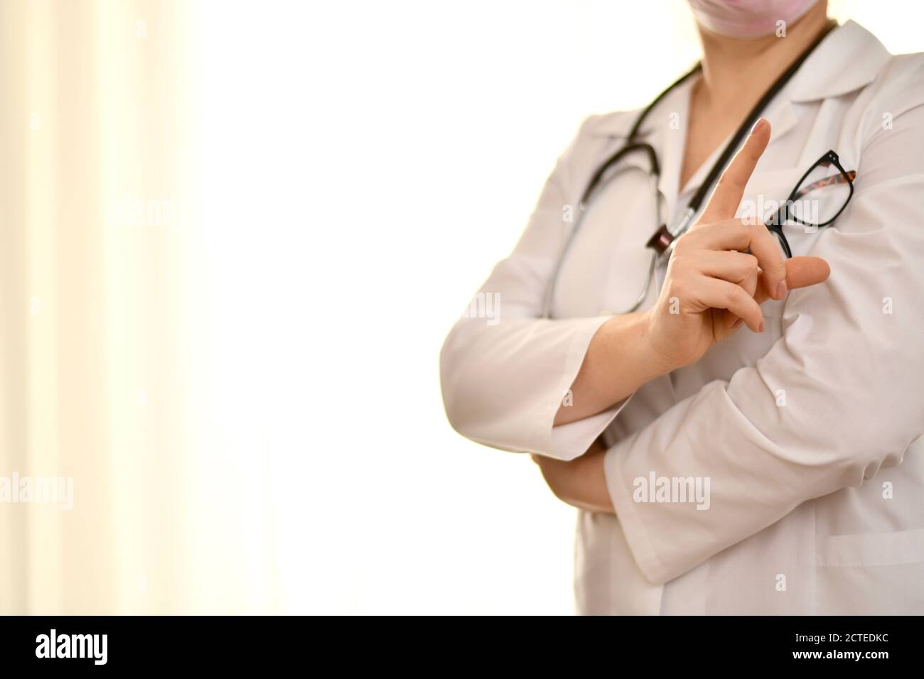 The doctor in a white robe with a stethoscope and glasses, shows a ...