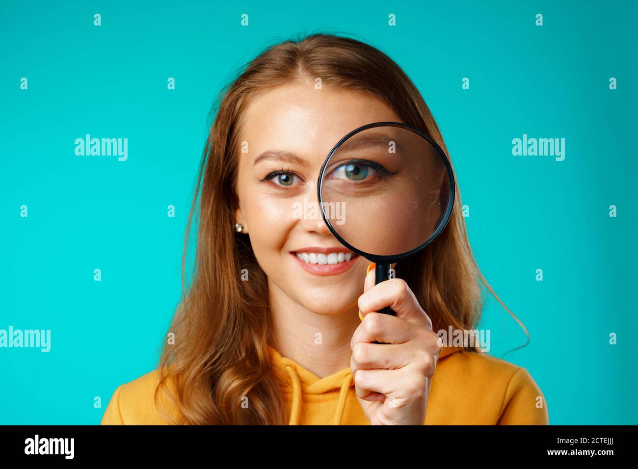 Young smiling woman looking through magnifying glass Stock Photo - Alamy