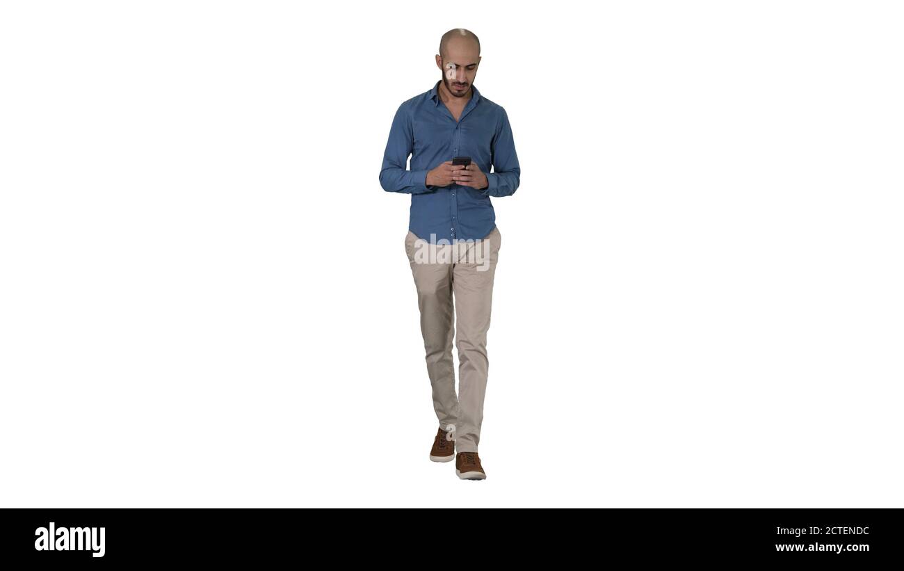 Man text messaging while walking on white background Stock Photo - Alamy