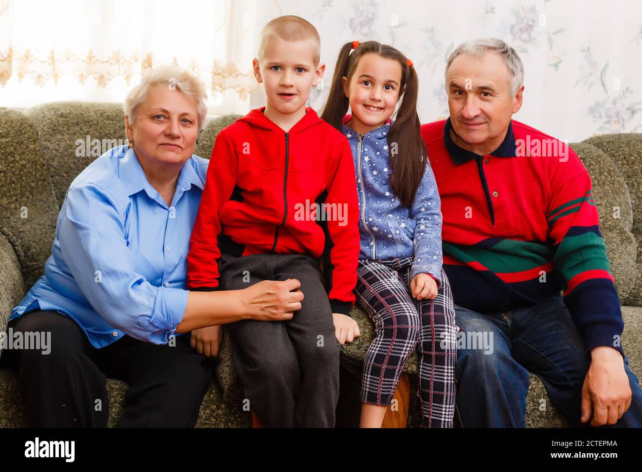 Grandparents and their young grandchildren relaxing at home Stock Photo ...